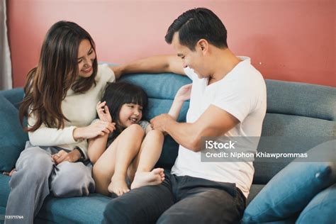 행복 한 쾌활 한 웃는 젊은 가족 어머니 아버지와 딸이 파란색 소파에 앉아서 모두 함께 연주 로즈 핑크 컬러 배경 벽 집에서 체재 2명에 대한 스톡 사진 및 기타 이미지