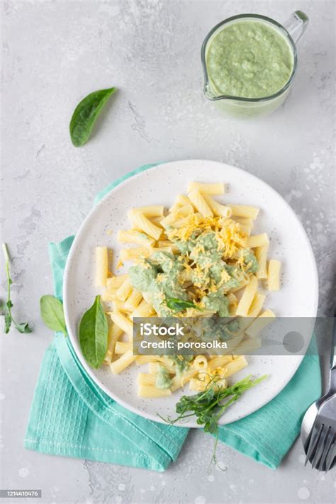 그린 크림 소스를 곁들인 펜네 파스타 세라믹 플레이트에 치즈와 마이크로 그린 밝은 회색 돌 배경 이탈리아 음식 맨 위 보기