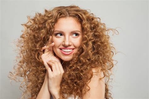 흰색 배경에 긴 자연 건강한 갈색 곱슬 머리와 귀여운 미소를 가진 예쁜 행복 한 젊은 여자의 패션 초상화 헤어 케어 헤어 트리트먼트 웰빙 및 미용 개념 20 24세에 대한