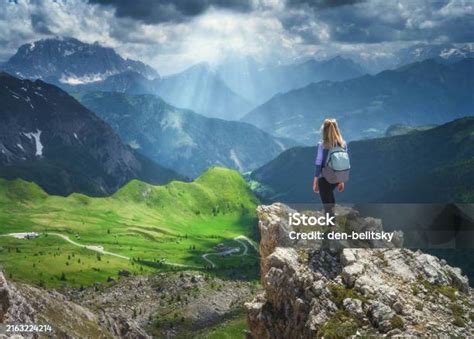 아름다운 고산 산 계곡의 바위에 배낭을 멘 소녀 여름에는 일몰에 푸른 초원 알프스에서 젊은 여자와 함께 풍경 구름 태양 광선과 극적인 하늘 돌로미티 이탈리아 하이킹 가냘픈에