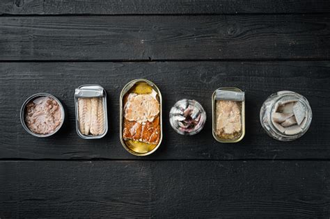 검은 색 나무 테이블 배경에 물고기의 다른 유형으로 통조림 캔의 구색 상단 보기 평면 누워 카피 스페이스와 텍스트 공간을 0명에