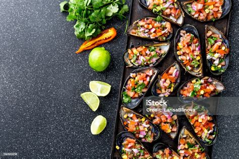 페루 음식 초로스 라 샬라카 큰 홍합 보라색 양파 토마토 옥수수 레몬으로 조미한 초로스 자파토 맨 위 보기 검은 색 배경입니다 전통 페루 요리 가리비에 대한 스톡 사진 및