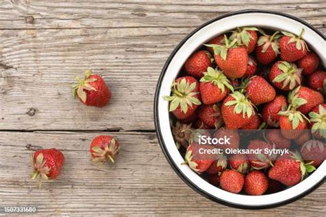 화창한 날에 소박한 나무 배경에 갓 딴 잘 익은 빨간 딸기로 가득 찬 빈티지 화이트 에나멜 그릇 비타민이 풍부한 여름 열매