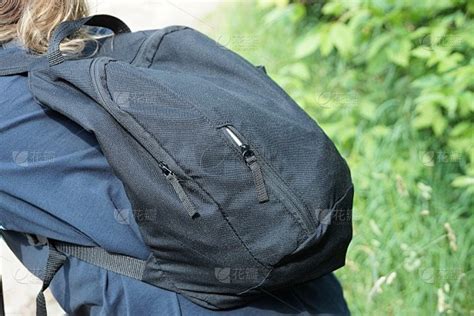 在街上，一个穿着蓝色衬衫的旅游女孩背着一个黑色的织物背包