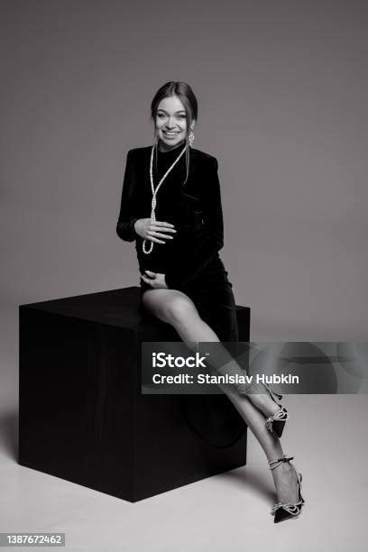 행복한 임산부는 어두운 배경에 대한 스튜디오에서 검은 드레스와 하이 힐 신발에 앉아 미소 25 29세에 대한 스톡 사진 및 기타 이미지 25 29세 갈색 머리 개념