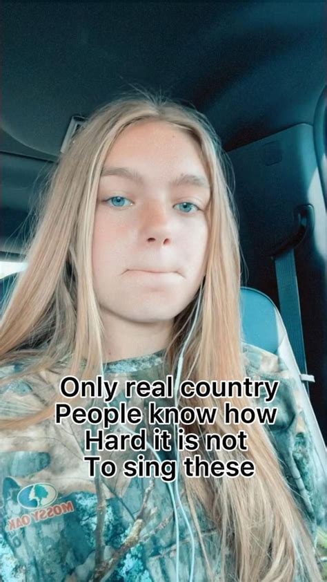 A Woman With Long Blonde Hair Sitting In The Back Seat Of A Car And Looking At The Camera