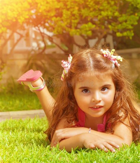 Маленькая девочка лежа вниз на зеленой траве Стоковое Фото изображение насчитывающей счастливо