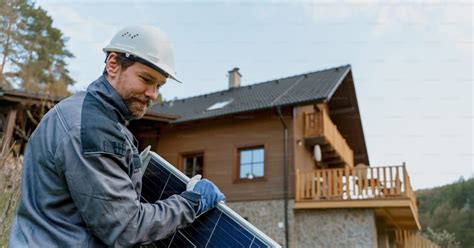 집에 태양 전지 패널 시스템을 설치하는 동안 태양 광 모듈을 운반하는 웃는 핸디맨 태양 광 설치자 사진 Unsplash의 슬로바키아 이미지