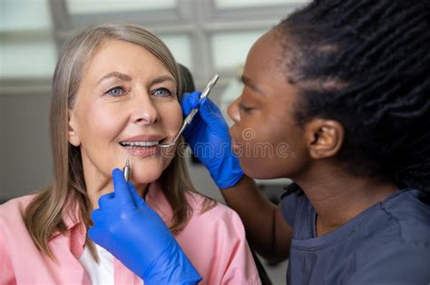 Doctor Holding Instrument Tool For Oral Examination Of Middle Aged