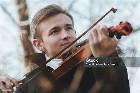 가을 자연백웅에서 바이올린을 연주하는 젊은 우아한 남자의 얼굴 활을 가진 악기 연습 야외 에서 음악 공연 취미와 예술의 개념 Classical Concert에 대한 스톡