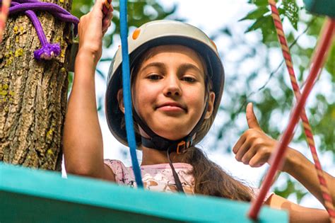 로프 파크 클라이밍 센터 보호 장비로 걷기 대회에 참가하는 십대 소녀는 클래스에 엄지 손가락을 보여줍니다 어드벤처 파크에서 게임 장애물을 통과합니다 익스트림 엔터테인먼트
