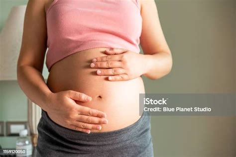 임신 한 여자는 그녀의 아이를 돌보는 동안 집에서 행복을 느낀다 임신 한 배에 아기를 들고 젊은 기대 어머니 출산 전 관리 및 여성 임신 개념 개념에 대한 스톡 사진 및