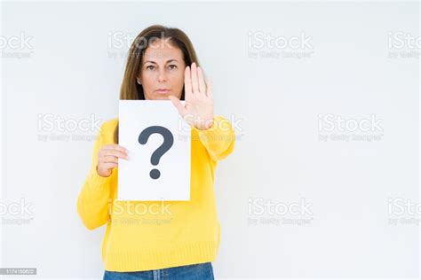 중년 여성 생각 하 고 심각 하 고 자신감 있는 표정으로 정지 기호를 하 고 고립 된 배경 위에 물음표 기호와 종이를 들고 방어