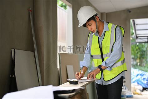 安全头盔和反光夹克的工程师与蓝图一起工作，检查施工现场的施工计划高清摄影大图 千库网