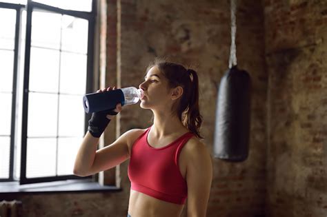 권투 체육관에서 젊은 아름 다운 운동 선수의 초상화입니다 운동 중에 병에서 음료를 마시는 권투 소녀 훈련 과정에서 많은 물을 마셔야합니다 권투 스포츠에 대한 스톡 사진 및