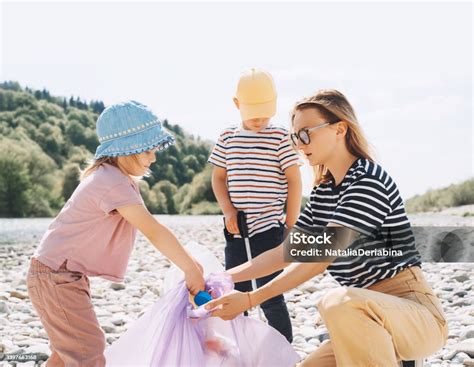 자원 봉사자 가족은 강 해변에서 플라스틱 쓰레기를 수거합니다 사람들은 자연을 깨끗하게 유지하고 쓰레기를 줍는 데 도움을줍니다 쓰레기에서 야외 공간을 청소하는 데 도움이되는