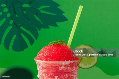딸기와 체리 붉은 과일 맛 빙수 또는 레몬을 곁들인 슬러시가 녹색 종이 잎으로 장식 된 녹색 종이 배경에 투명한 일회용 컵에 담겨 있습니다 과일에 대한 스톡 사진 및 기타
