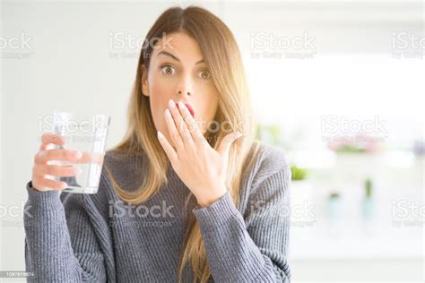 물 집에서 손으로 커버 입 실수 두려움의 표현에 대 한 수치심과 충격의 유리를 마시는 젊은 아름 다운 여자는 침묵 비밀 개념에에서 무서 워 가리기에 대한 스톡 사진 및 기타