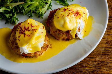 계란 베네딕트 신선한 아보카도와 토마토를 곁들인 전통적인 클래식 미국 식당 또는 프렌치 비스트로 브런치 메뉴 수제 홀란다이즈 소스를 데친 달걀 위에 얹고 아보카도를 영국식