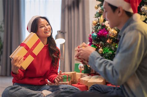 빨간 스웨터를 들고 기쁨에 가득 찬 여자 남자와 크리스마스를 축하 남자 축제 분위기에는 장식 된 트리와 화려한 선물이 포함되어