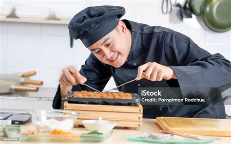 초상화 잘 생긴 전문 일본 남성 요리사 검은 유니폼을 입고 모자를 쓰고 요리하고 타코야키 거리 음식을 만들고 자신감있게 웃고