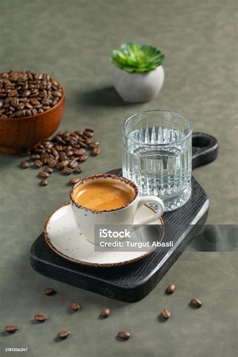 물과 커피 원두를 곁들인 더블 에스프레소 더블 에스프레소의 세라믹 컵으로 나무 판에 물 한 잔과 함께 제공됩니다 커피 원두가