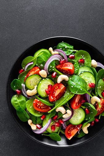 신선한 오이 토마토 양파 석류 참 깨와 검은 배경에 캐슈 너트와 시금치 샐러드 건강 한 채식 음식입니다 상위 뷰 건강한 생활방식에 대한 스톡 사진 및 기타 이미지 Istock