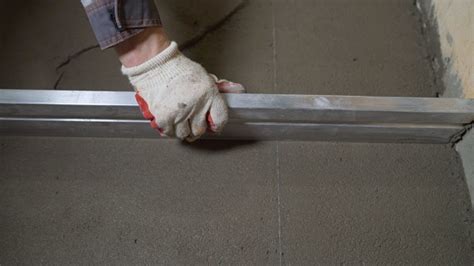 석고 벽에 석고를 바르는 건설 노동자 건축업자는 건축 통치자로 폭기 된 콘크리트 블록 벽에 석고를 펴고 있습니다 건설 도구로 벽의 모르타르를 평평하게합니다