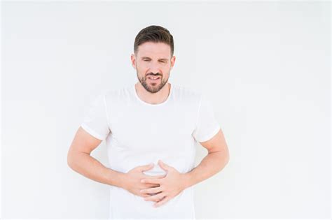 이상의 캐주얼 티셔츠를 입고 젊은 잘생긴 남자 고립 속에 손으로 배경 때문에 소화 불량 고통 스러운 질병 기분이 나쁘다 통증 개념입니다 T 셔츠에 대한 스톡 사진 및 기타