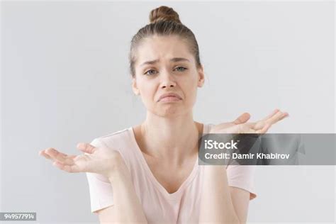 마치 그녀가 현재 상황을 어떻게 해야할지 모르는 손실에 회색 배경에 고립 된 감정적인 젊은 여자의 근접 촬영 곡선 팔과 손 입 력한 제스처를 보여주는 여자에 대한 스톡 사진