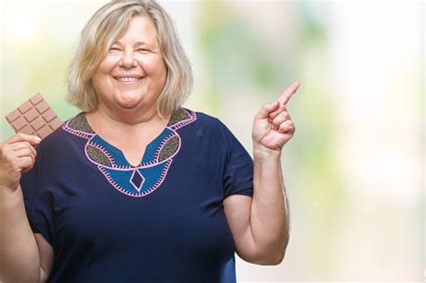 시 니 어 플러스 사이즈 백인 여자에 초콜릿을 먹는 절연 배경 쪽으로 손 및 손가락으로 가리키는 매우 행복 가리키기에 대한 스톡 사진 및 기타 이미지 Istock