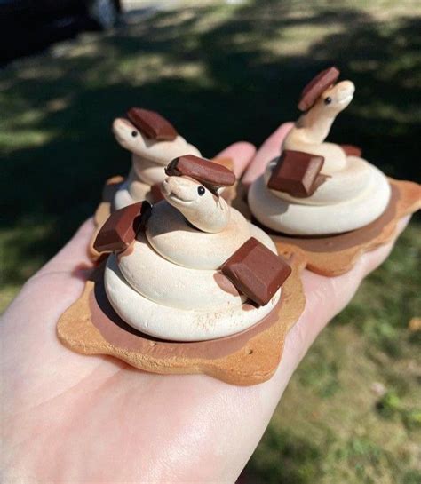 Two Small Figurines Sitting On Top Of A Piece Of Bread In The Palm Of Someones Hand