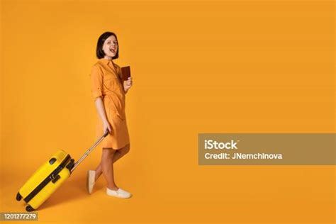 밝은 노란색 배경에 가방을 가진 예쁜 여자입니다 여행 가방을 가진 행복한 소녀 여행자 갈색 머리에 대한 스톡 사진 및 기타 이미지 갈색 머리 개인 장식품 관광