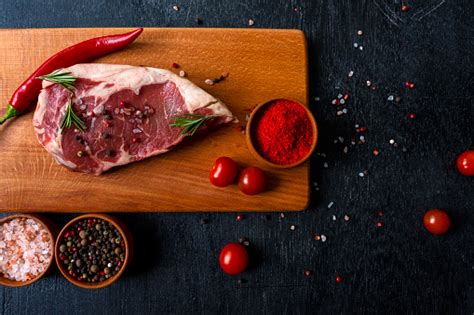 나무 테이블에 나무 도마에 리비아이 쇠고기 고기의 원시 조각은 고추 후추 파프리카와 히말라야 소금으로 장식 토마토 누적 신선한 음식 바베큐를위한 모든 것 0명에 대한 스톡