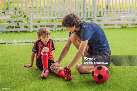 빨간 축구 유니폼을 입은 귀여운 소년과 그의 트레이너 또는 아버지가 야외에서 축구 축구를 하고 있다 아이들이나 아빠와 함께 스포츠를 하는 활동적인 아이 여름에 즐거운 미소를