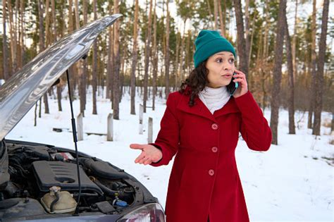 충격을 받은 중년 여성은 깨진 차 근처에 서서 눈 덮인 도로에서 차가 고장나는 동안 길가의 도움을 요청하려 했습니다 자동차 보험