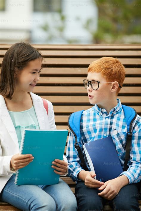 교과서를 들고 야외 벤치에 앉아 함께 수업에 대해 토론하는 여학생과 남학생 사진 Unsplash의 러시아 이미지