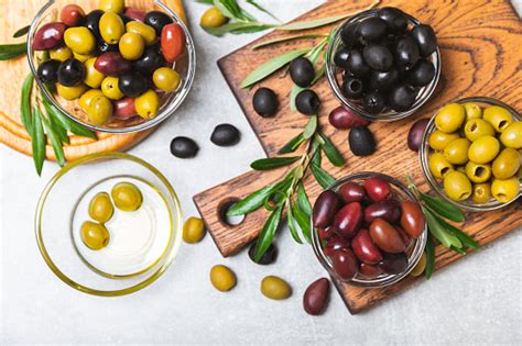 흰색 바탕에 녹색 빨간색 검은색 올리브 세트 그릇에 담긴 다양한 종류의 올리브와 신선한 올리브 잎을 곁들인 올리브 오일 진미지중해식 주방 복사 공간 갈색에 대한 스톡 사진