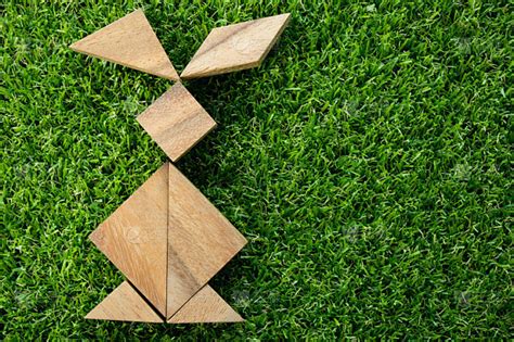 人工绿草背景下的兔形木制七巧板快乐复活节概念