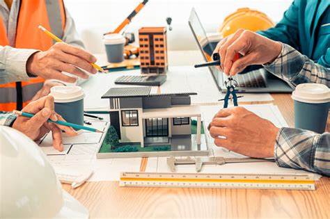 건축가가 디지털 태블릿을 들고 새로운 부동산 프로젝트를 진행하면서 책상에 앉아 엔지니어링 도구와 건축 모형 집 건물 및 시공을 클로즈업하는 장면 개인 장식품에 대한 스톡