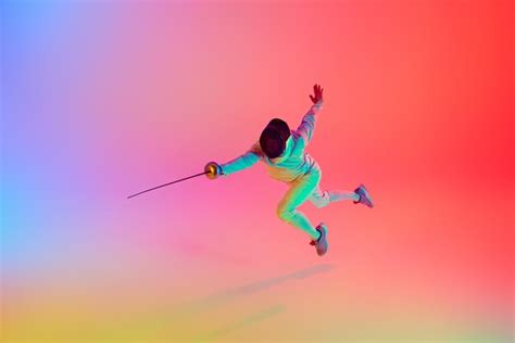 Young Skilled Fencer In Full Gear In Attacking Pose With One Arm Extended Forward Holding Rapier