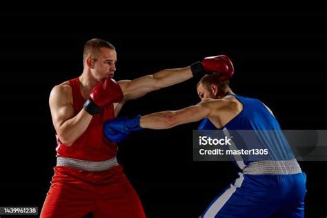 파란색과 빨간색 스포츠 유니폼을 입은 남성 프로 복서들은 어두운 배경에 고립된 펀치를 연습합니다 스포츠 경쟁 훈련 에너지의 개념 20 24세에 대한 스톡 사진 및 기타