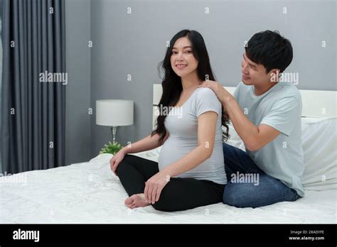 Husband Massaging Shoulders Of His Pregnant Wife On A Bed She Suffering From Back Pain Stock