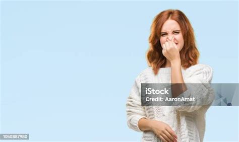 겨울 스웨터 뭔가 냄새 나 고 역 겨 운 냄새 참을 냄새 손가락으로 잡고 숨을 코에 입고 하는 고립 된 배경 위에 젊은 아름 다운 여자 나쁜 냄새 개념입니다 가을에 대한