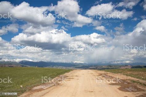흐린 하늘을 배경으로 수평선에 눈 덮인 봉우리와 산맥이있는 목초지를 통과하는 길 0명에 대한 스톡 사진 및 기타 이미지 0명 거리 경관 Istock