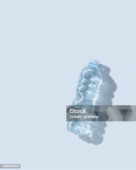 햇빛이 비치는 작은 플라스틱 병에 담긴 깨끗한 식수 파란색 배경에 그림자 복사 공간 완전히 닫힌 병 물 반 리터 오염 플라스틱