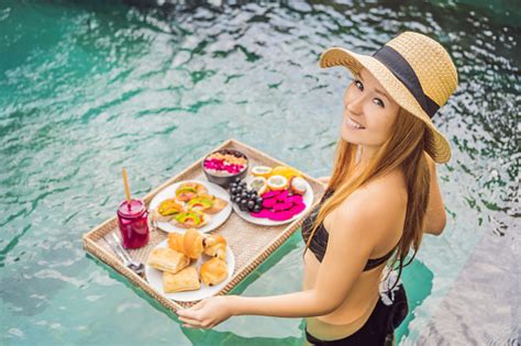 수영장에서 아침 식사 트레이 고급 호텔에서 떠있는 아침 식사 수영장에서 휴식을 취하는 소녀는 스무디를 마시고 과일 접시 호텔 수영장 옆에서 스무디 그릇을 먹습니다 이국적인