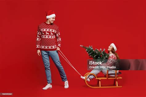 전신 젊은 커플 친구 두 남자 여자 20 S 스웨터 모자 보유 전나무 를 타고 썰매 일반 빨간 배경 스튜디오 초상화 새해 복 에 고립 된 2022 축하 메리 호 X마스 휴가