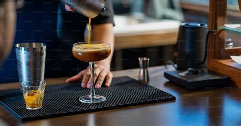 아시아 남자 바리스타가 셰이커에서 아이스 블랙 커피를 흔들고 커피숍의 바 카운터에서 칵테일 잔을 따르고 있습니다 고객에게 차가운 음료를 제공하는 남성 커피 숍 주인 중소