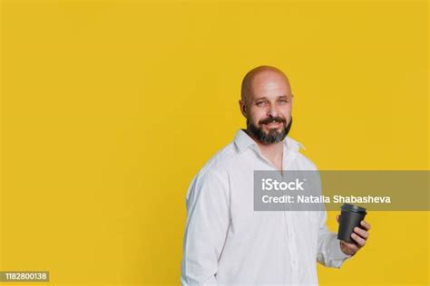 흰색 셔츠를 입은 잘생긴 진지한 중년 남성이 미소를 지으며 복사 공간이 있는 노란색 배경에 커피 한 잔을 들고 있다 노인의